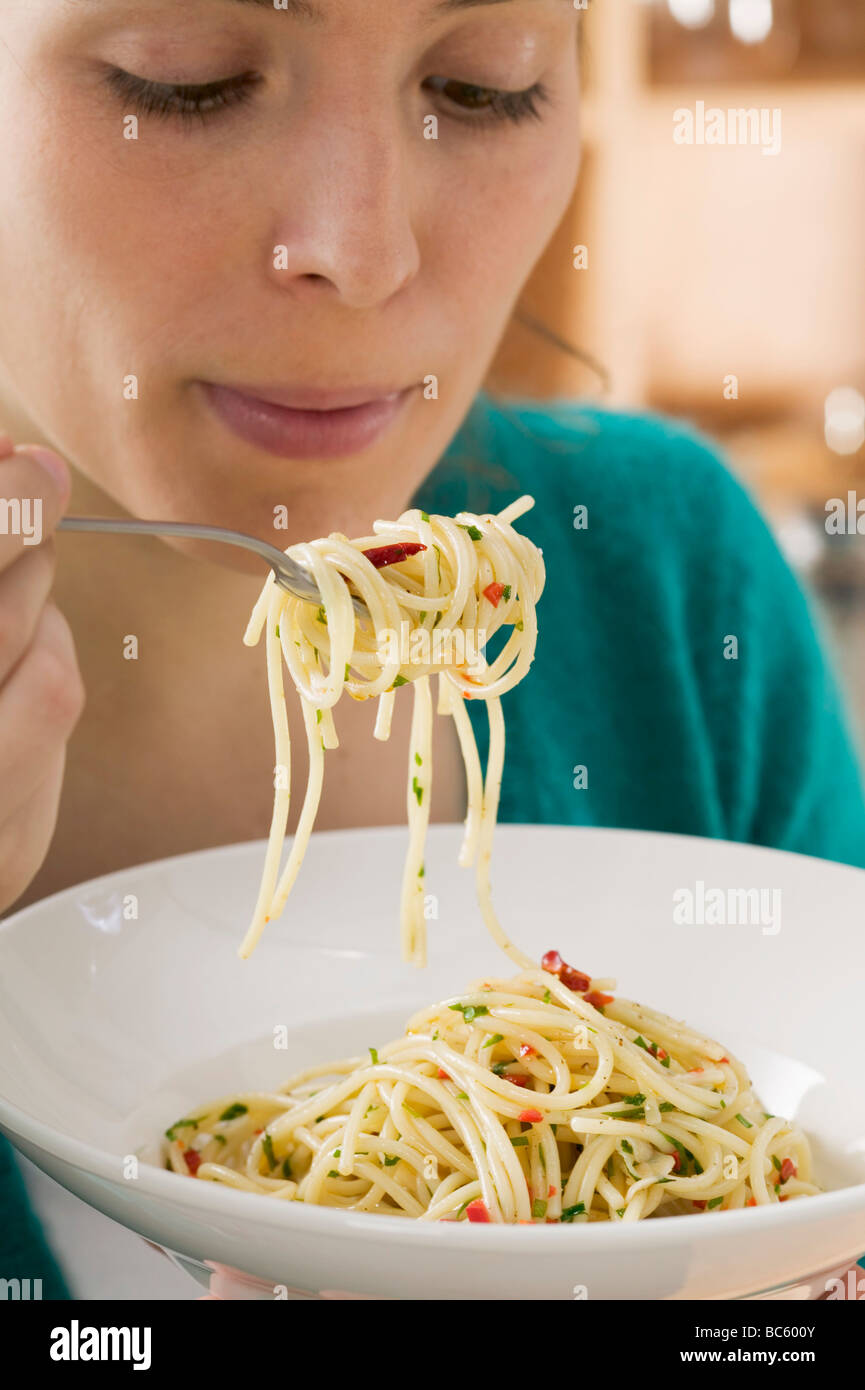 Young woman eating spaghetti with chillies Stock Photo - Alamy