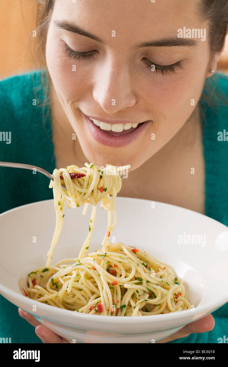 Young woman eating spaghetti with chillies Stock Photo - Alamy