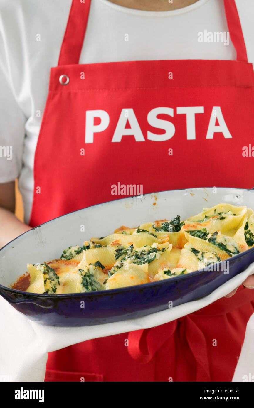 Woman in apron serving baked pasta dish Stock Photo - Alamy