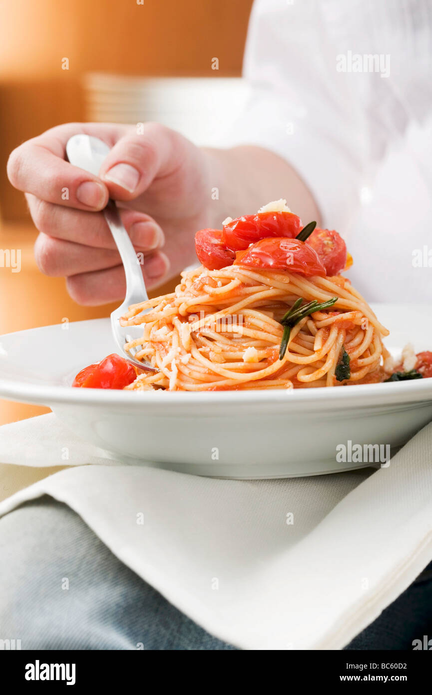 Person eating spaghetti with tomatoes and rosemary Stock Photo - Alamy