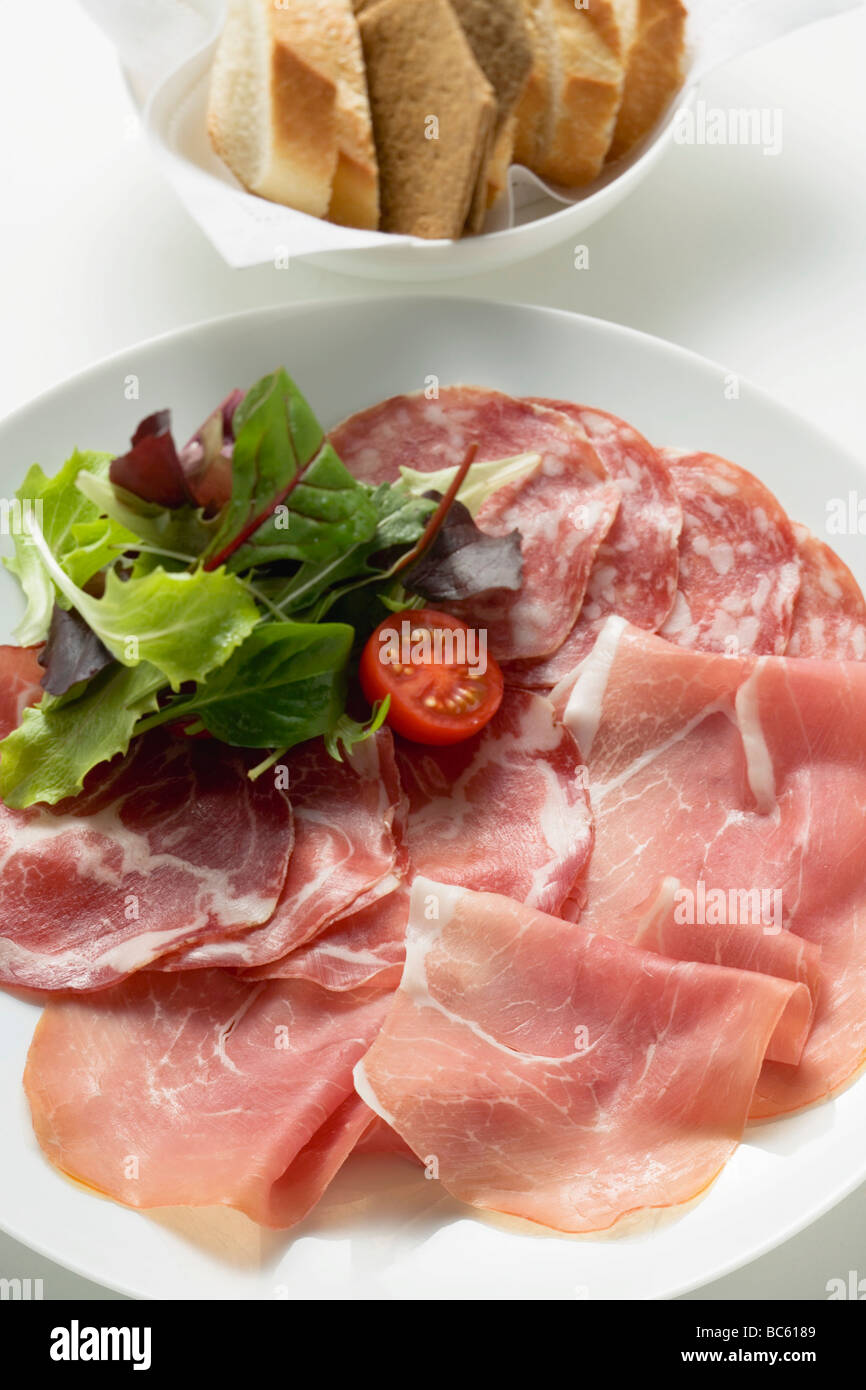 Raw ham and salami on plate, baguette slices Stock Photo - Alamy