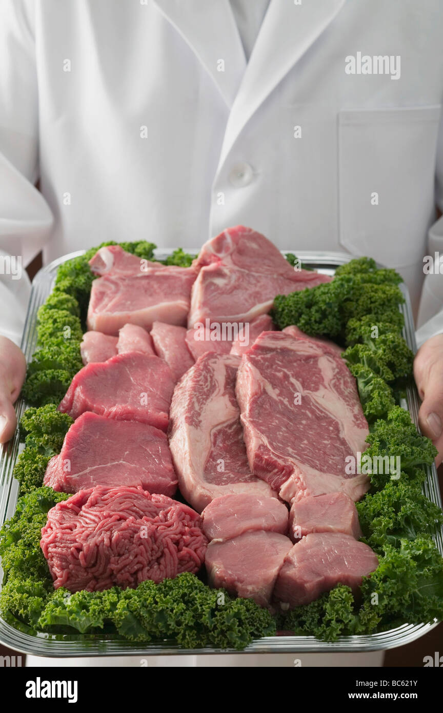 Butcher holding tray of various cuts of meat Stock Photo - Alamy