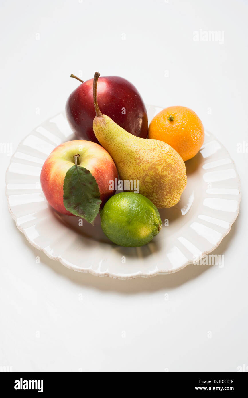 Core fruit and citrus fruit on white plate Stock Photo - Alamy