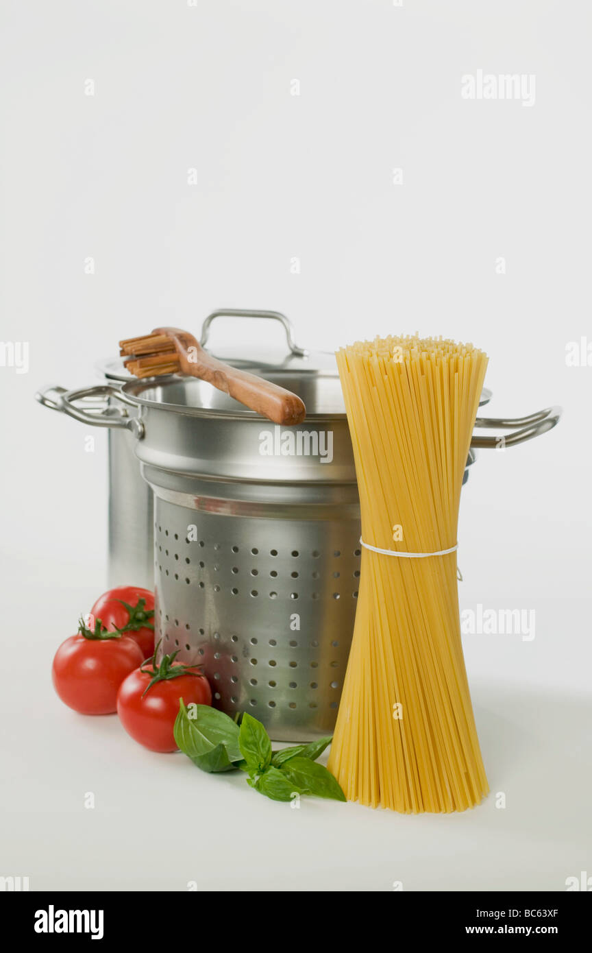 Spaghetti, pans, spaghetti server, tomatoes and basil Stock Photo - Alamy