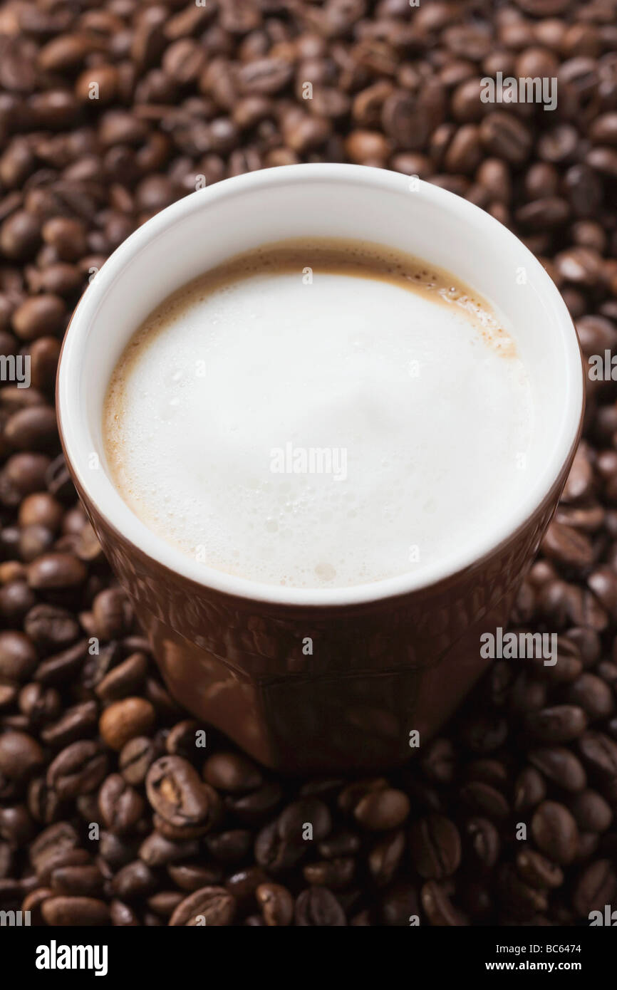 Cup of coffee with milk froth on coffee beans Stock Photo - Alamy