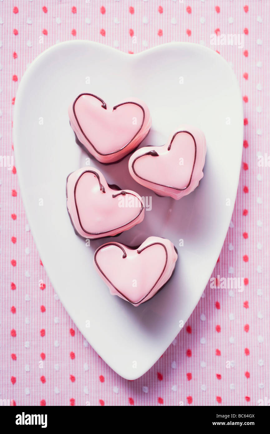 Four pink heart-shaped petit fours on plate Stock Photo - Alamy