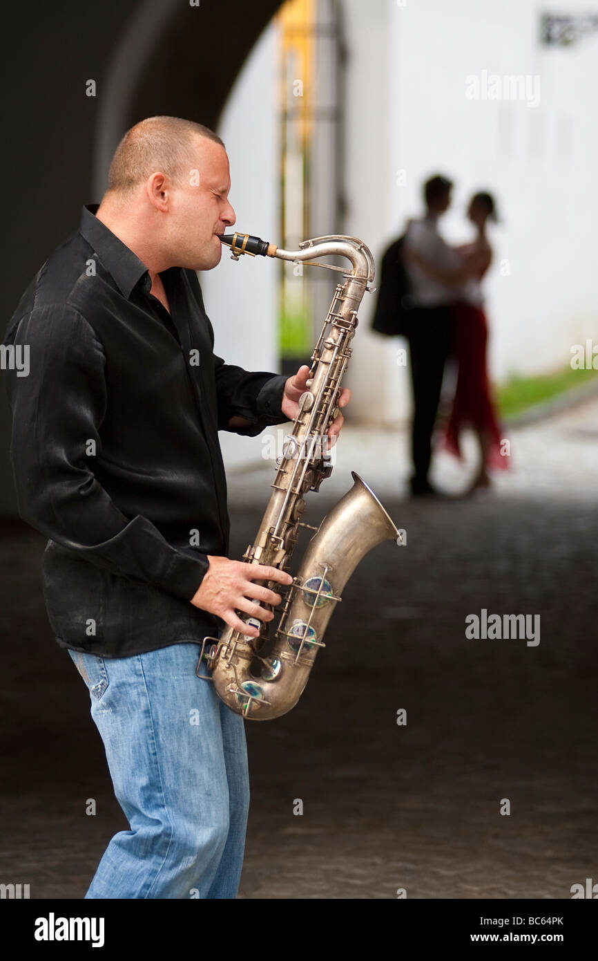 A street musician playing his saxophone serenades two young lovers ...