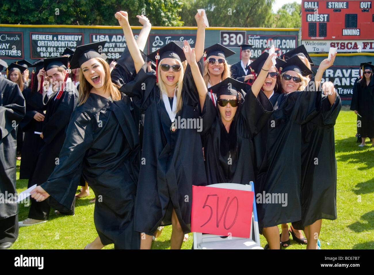 Happy senior girls in cap and gown cheer on graduation day in San ...
