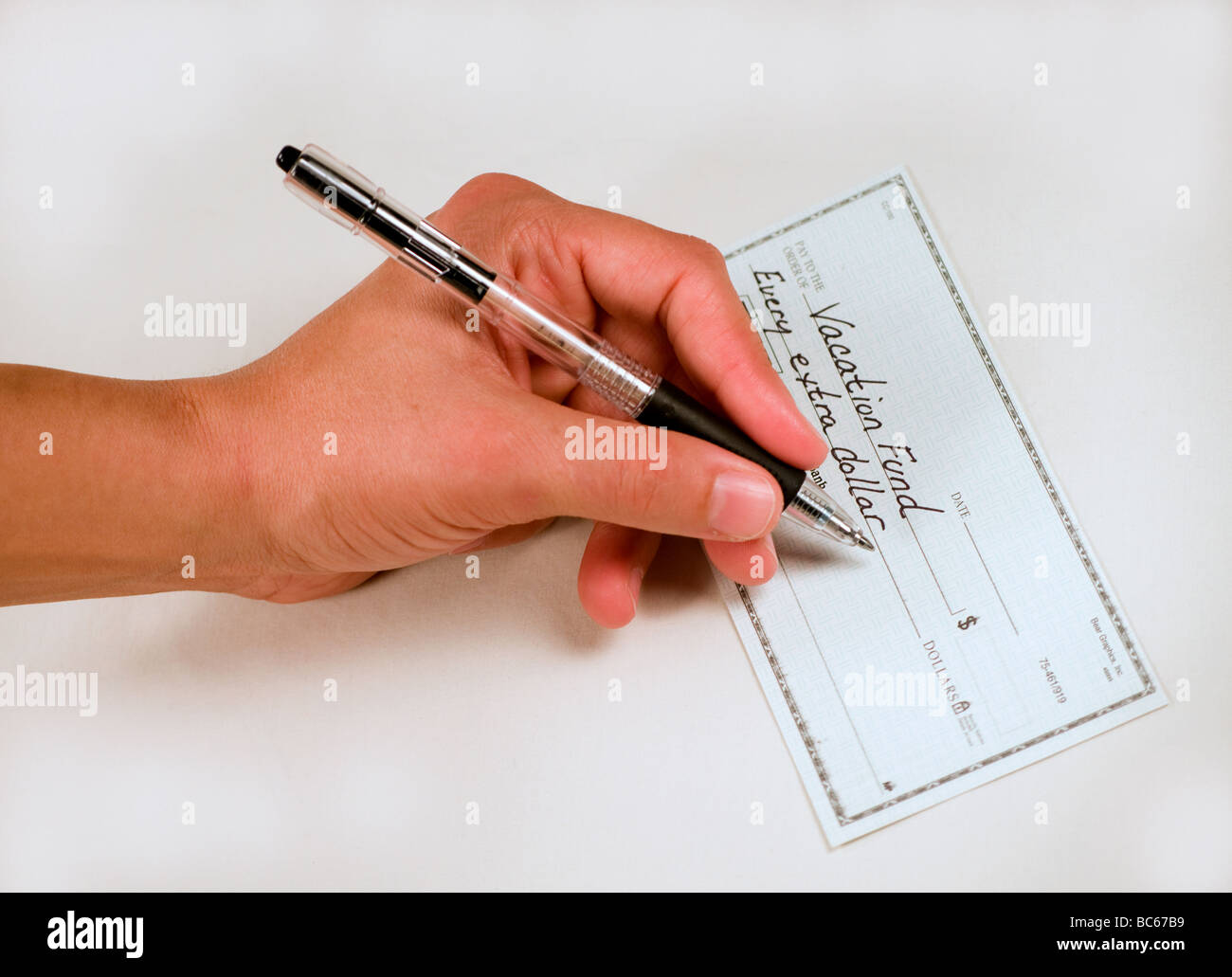 closeup of hand writing check to Vacation fund for Every extra dollar ...