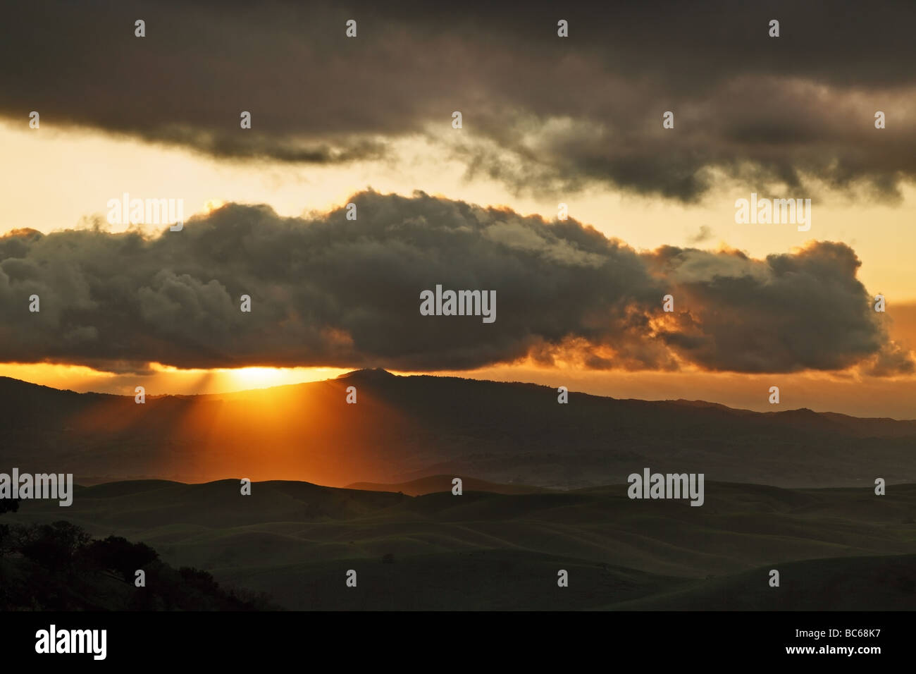 Orange sun rays on rolling hills Stock Photo - Alamy