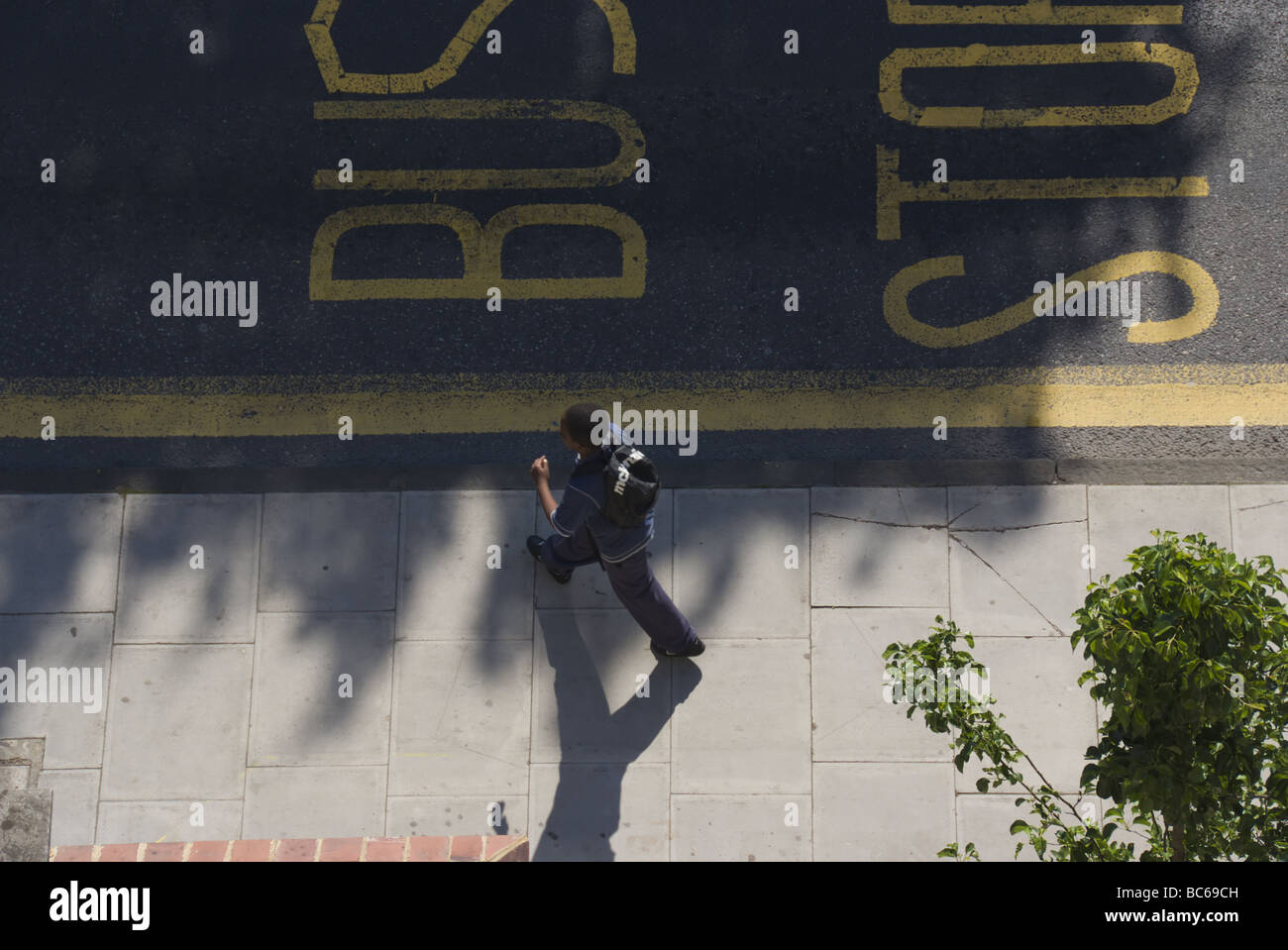A young boy walking on the pavement close to a bus stop Stock Photo - Alamy