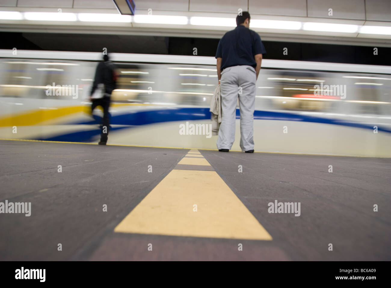 Passengers watch as a train rushes through the platform at Waterfront ...