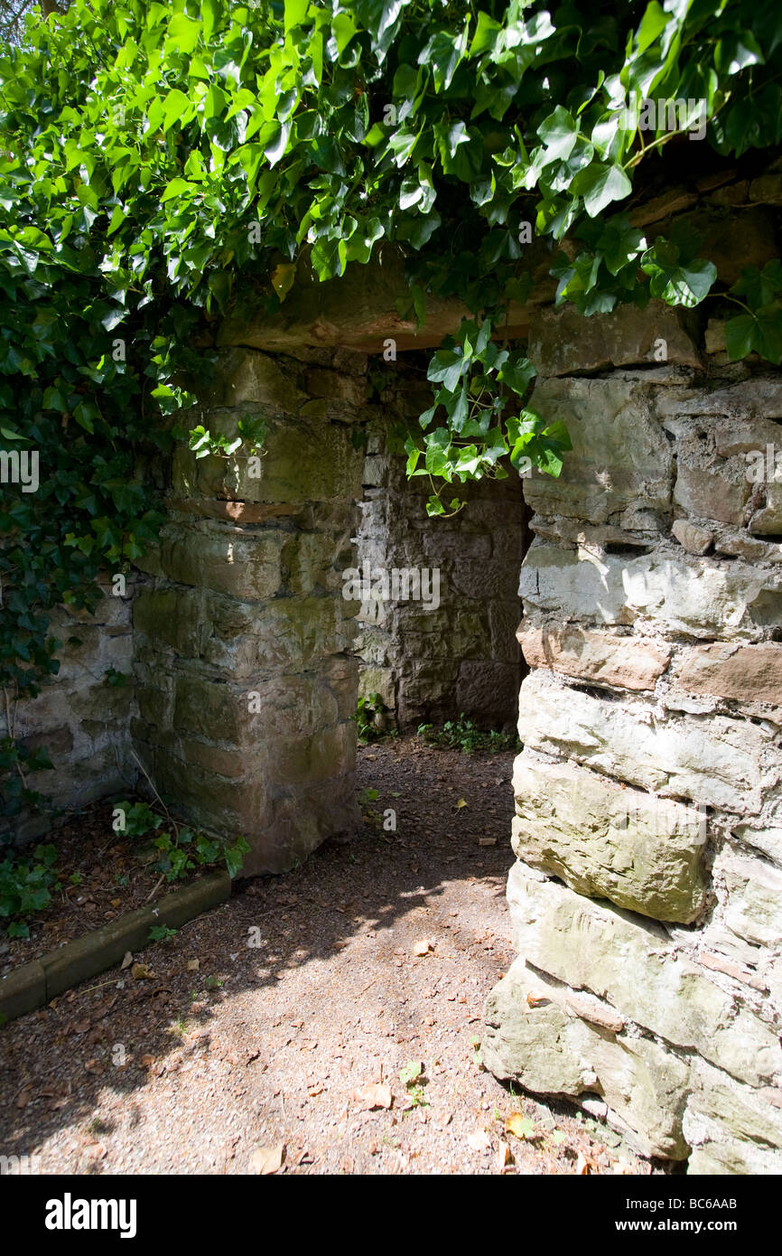 Passageway in garden wall with stone surrounds, overhung with ivy Stock ...