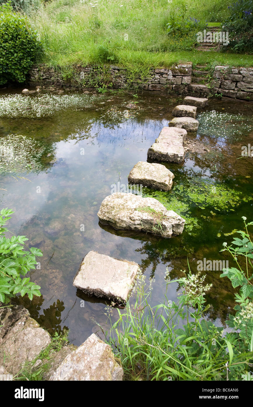 A row of stepping stones crossing a shallow stream onto stone steps and ...