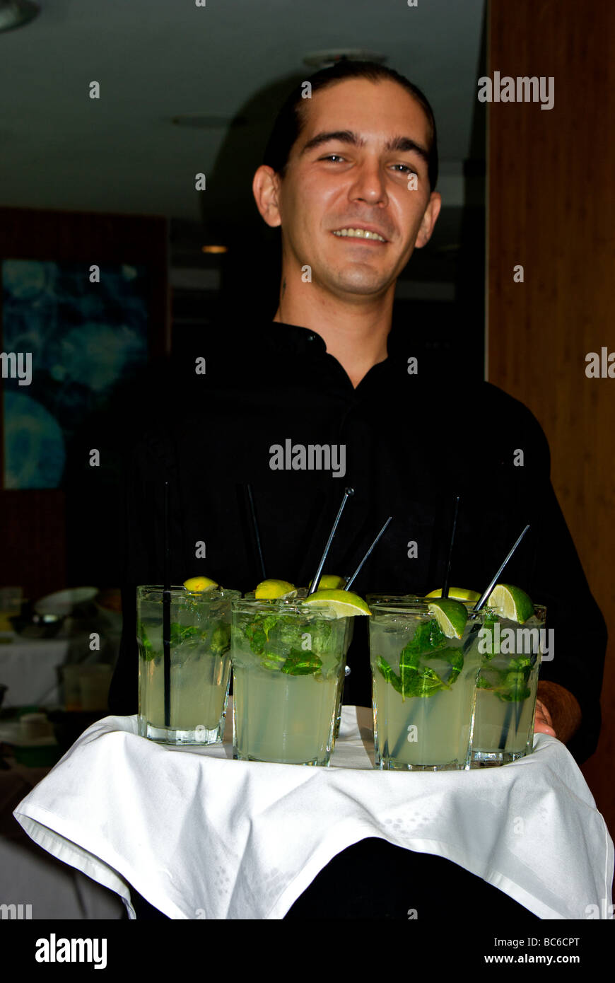 Waiter with trayful of white rum lime mint flavoured mojitos in ...