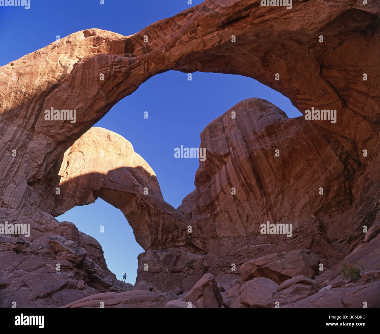 Tiny figure of a person standing under 2 huge natural arches Stock ...