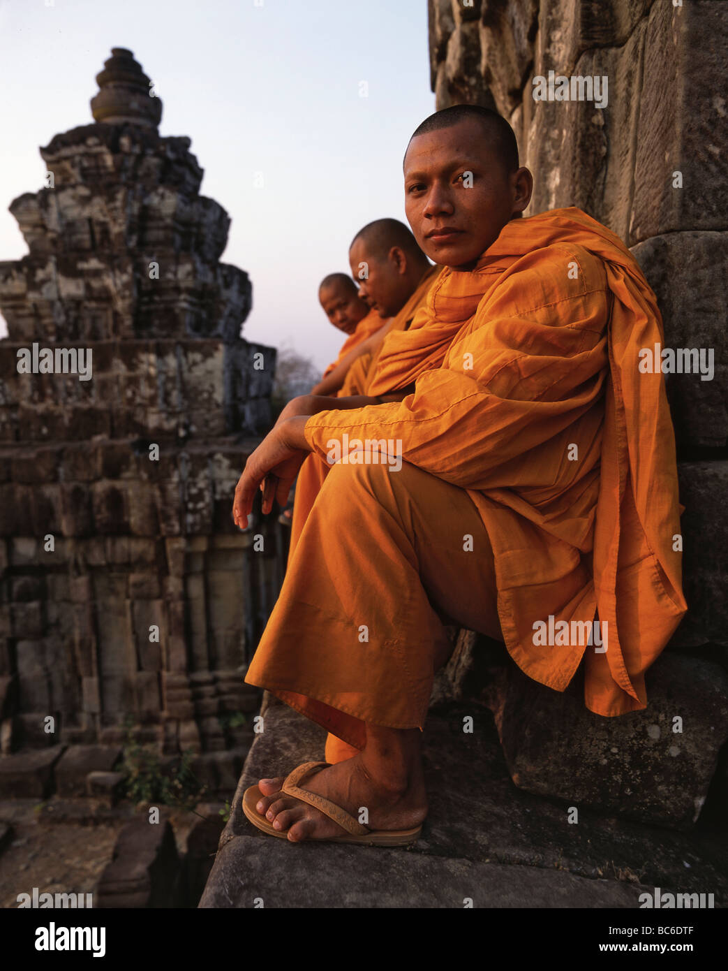 Three Buddhist monks relax on a temple in Angkor Stock Photo - Alamy