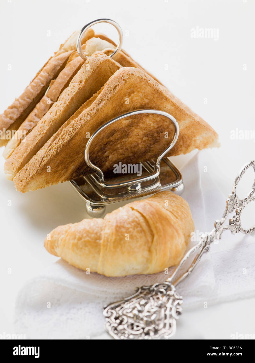 Toast in toast rack, croissant and pastry tongs Stock Photo - Alamy