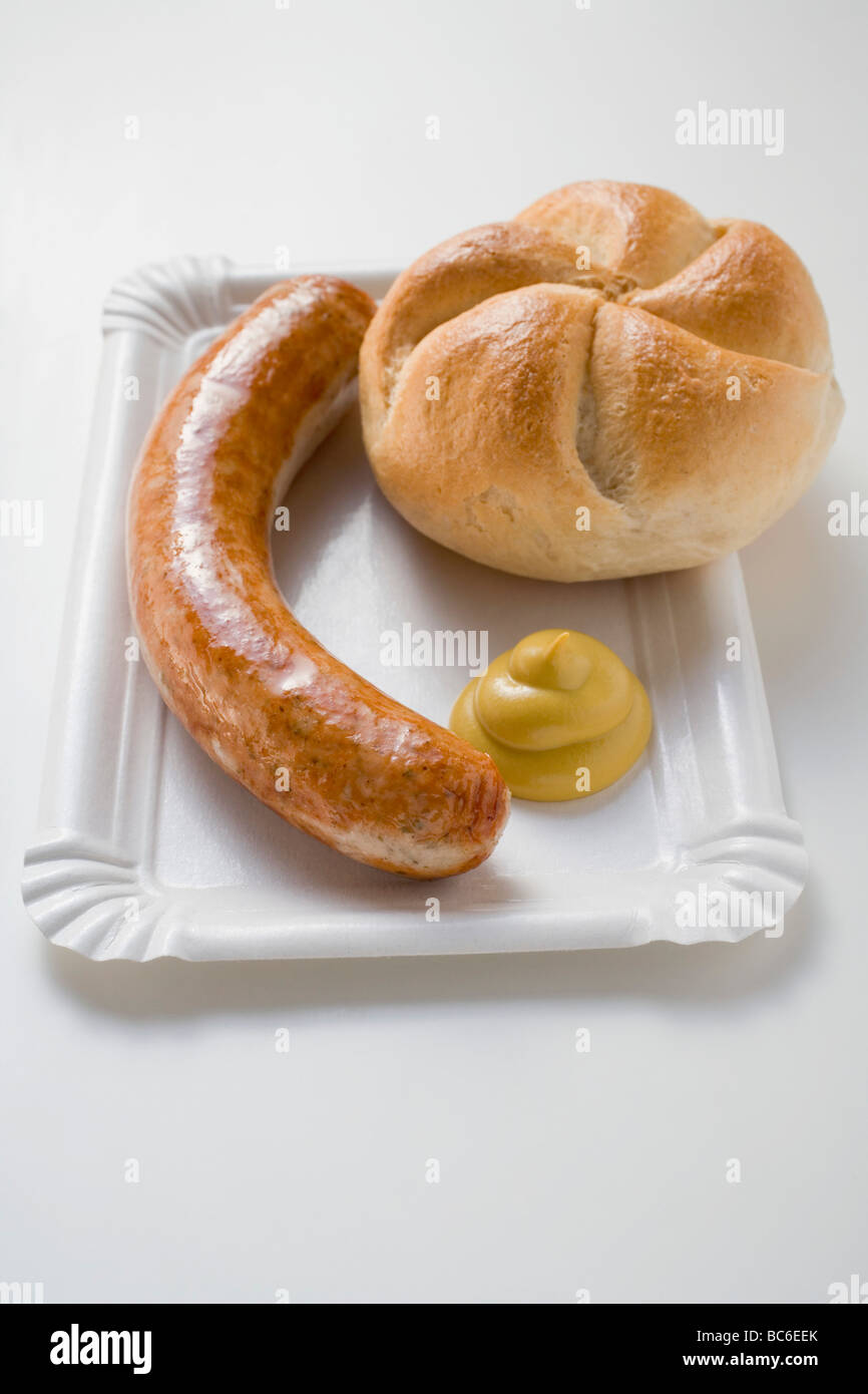 Sausage (bratwurst) with mustard & bread roll on paper plate Stock ...