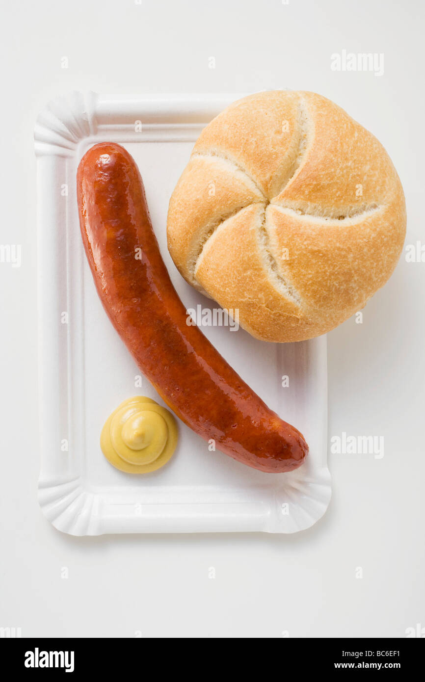 Sausage (bratwurst) with mustard & bread roll on paper plate Stock ...