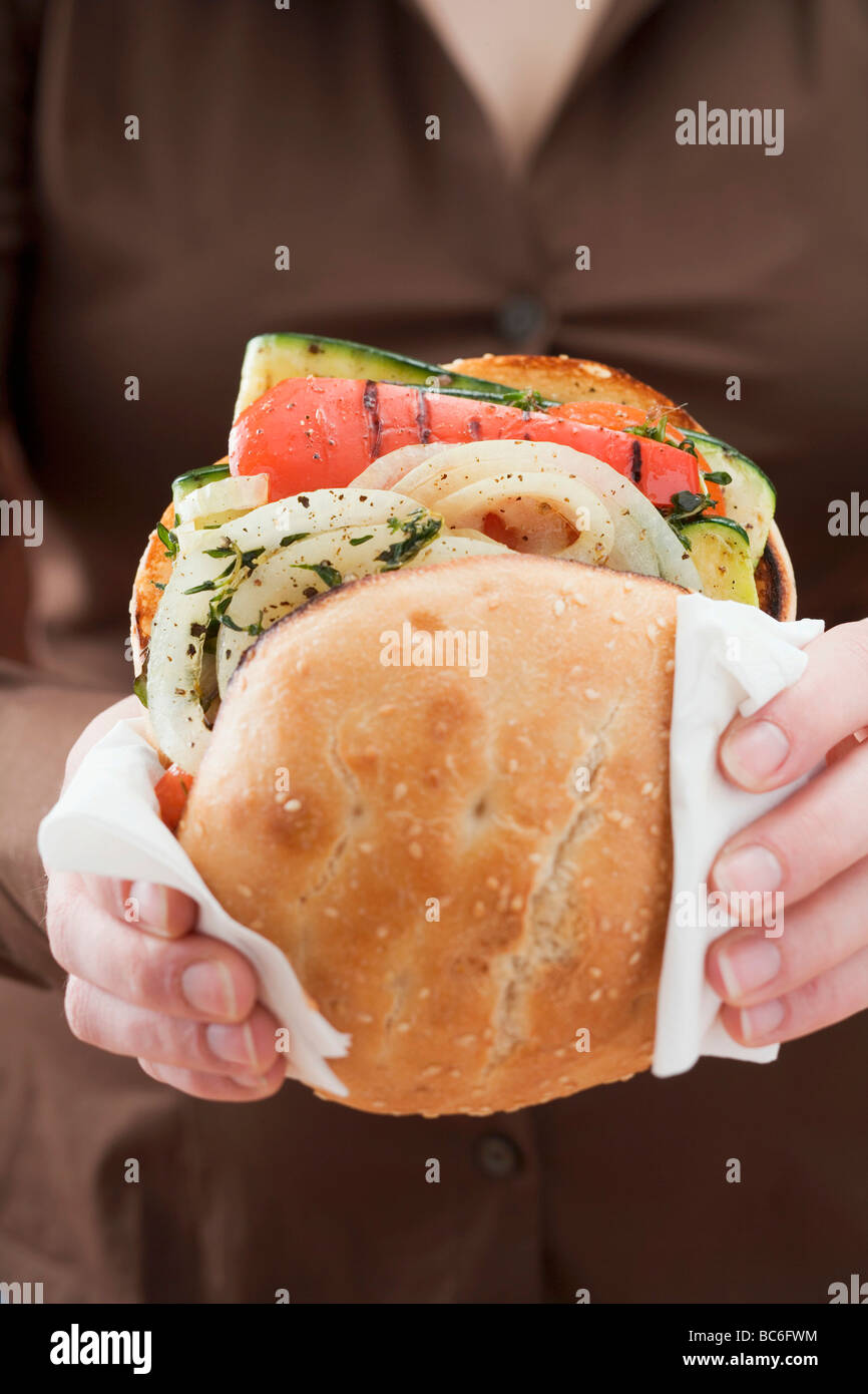 Woman holding toasted roll filled with grilled vegetables Stock Photo ...