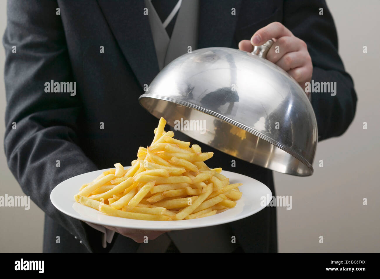 Butler lifting serving dome from plate of chips Stock Photo - Alamy