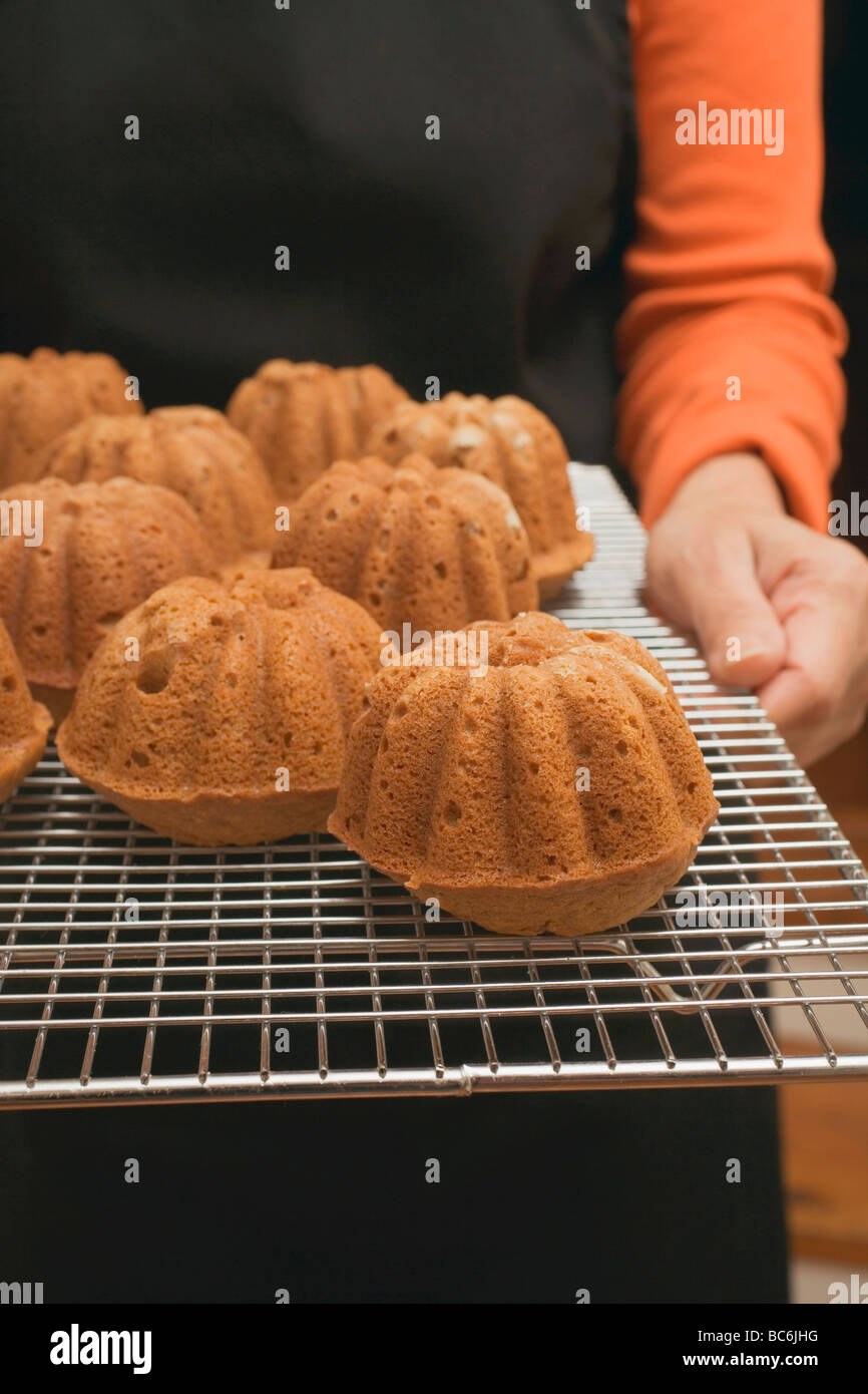 Hands holding freshly baked cakes on cake rack Stock Photo - Alamy