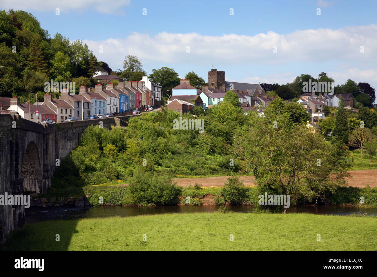 The River Towy flowing under a stone bridge below the hillside town of ...