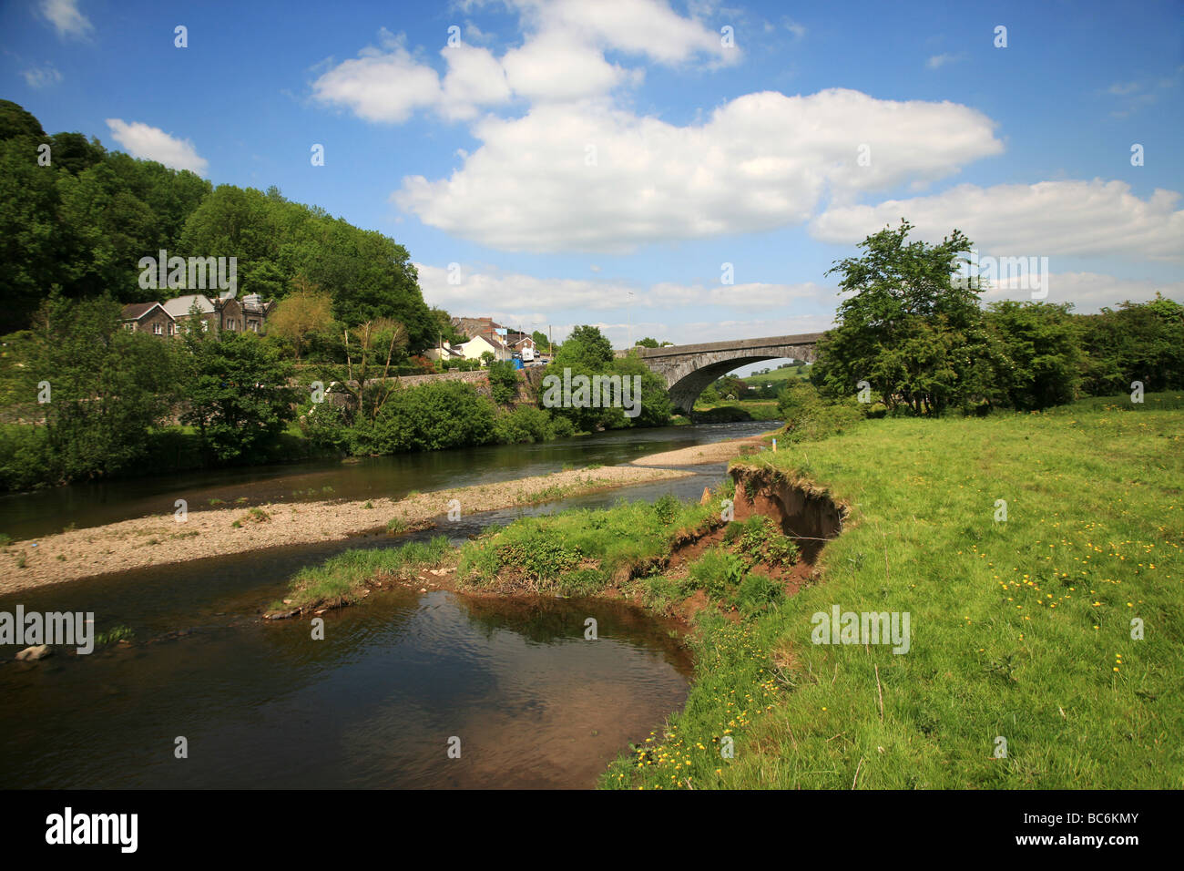 The River Towy flowing under a stone bridge below the hillside town of ...