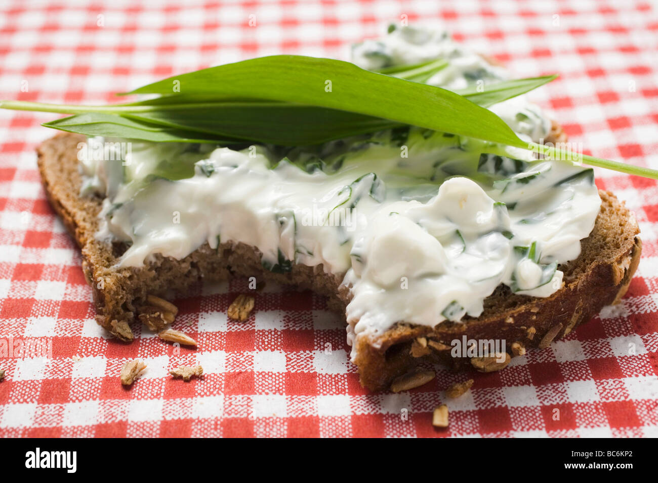 Quark and ramsons on wholemeal bread, a bite taken Stock Photo - Alamy