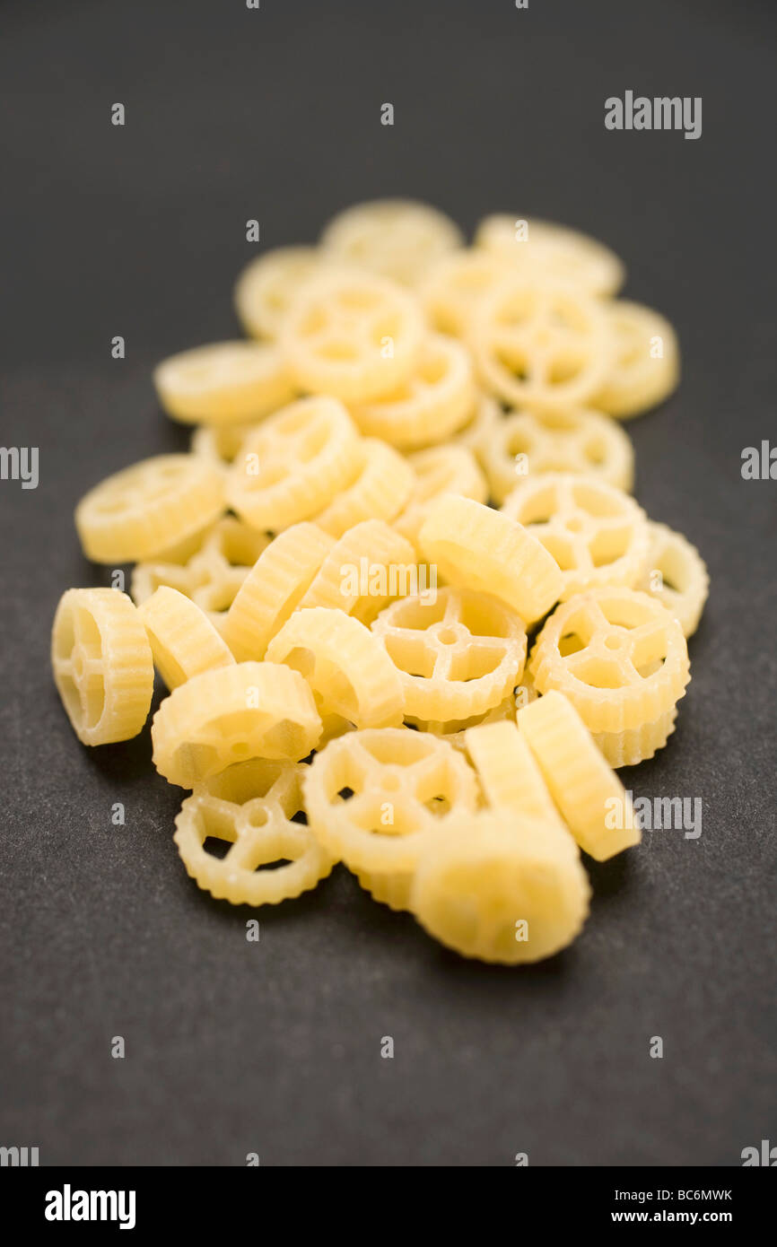 Wagon wheel pasta on black background Stock Photo - Alamy