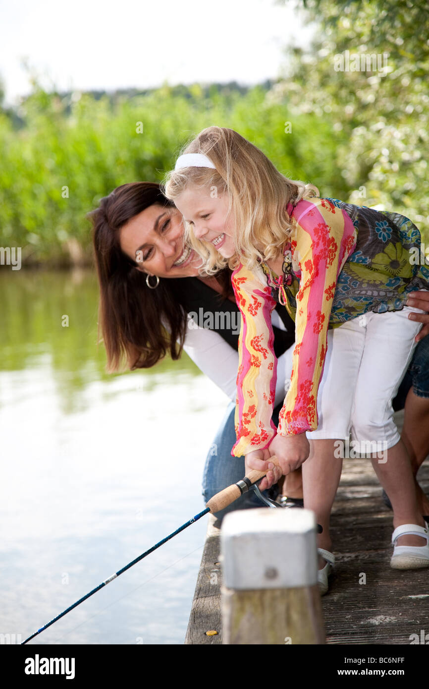 Cute young girl trying to catch a fish with mom watching over her Stock ...