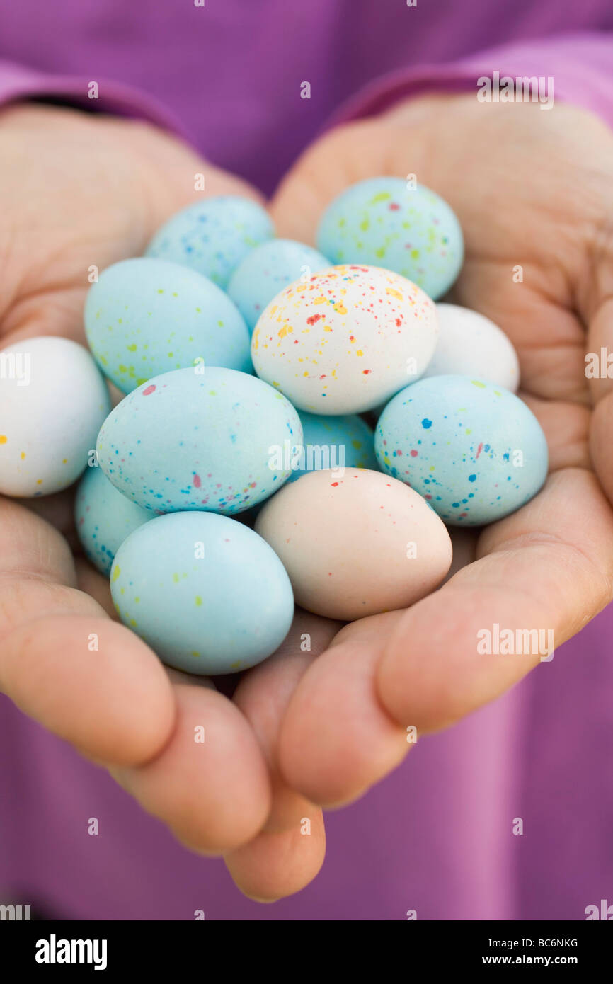Hands holding chocolate eggs with pastel-coloured candy shells Stock ...