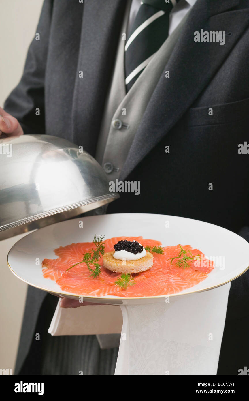 Butler serving smoked salmon with caviar Stock Photo - Alamy