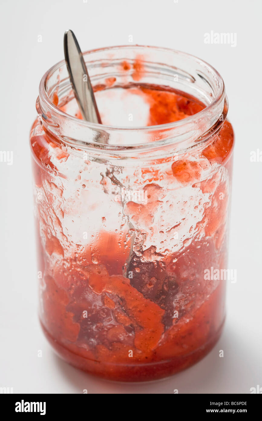 Jam jar with spoon and remains of strawberry jam Stock Photo - Alamy