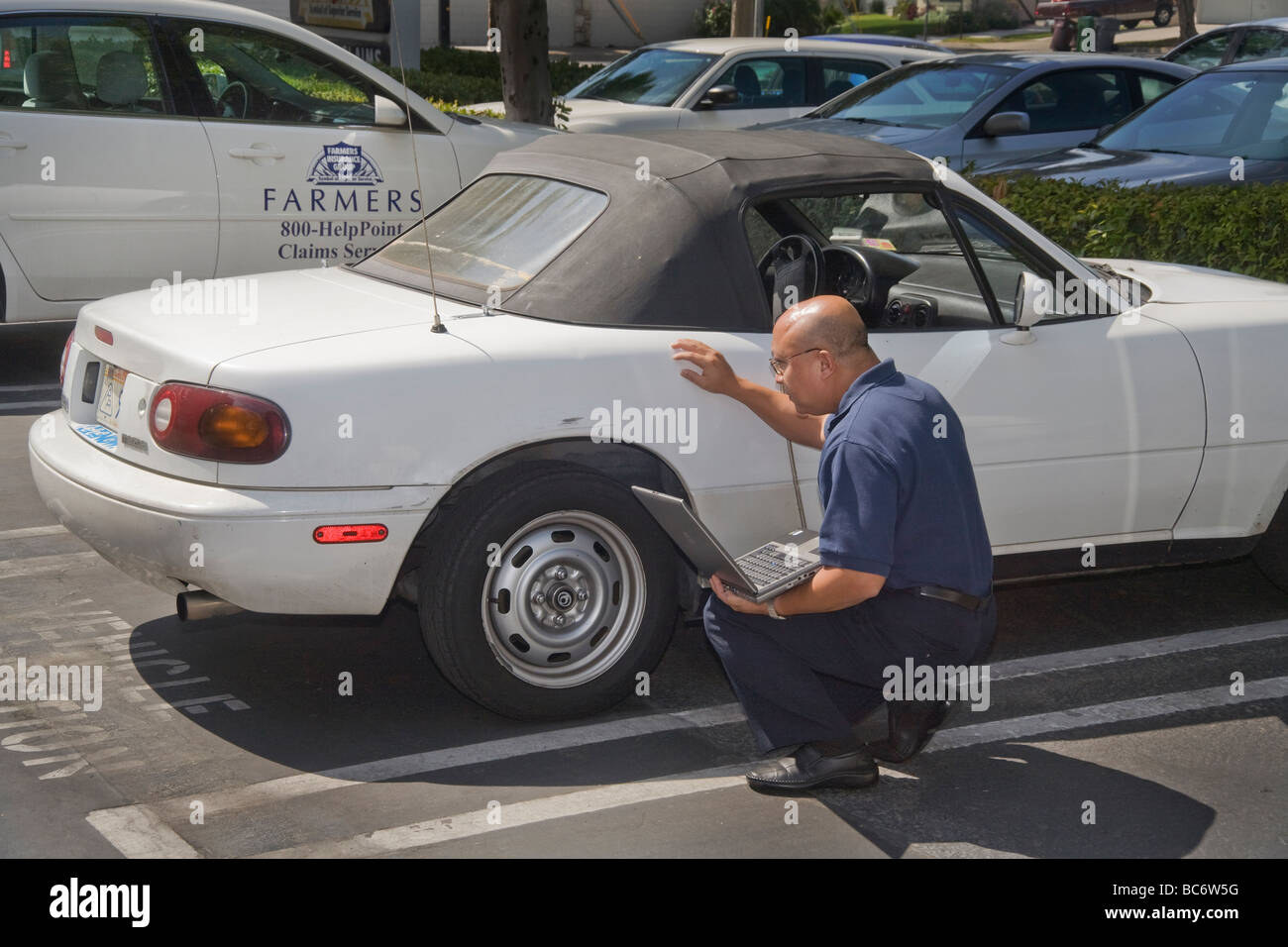 An adjuster evaluates damage to a car for an insurance claim Note ...