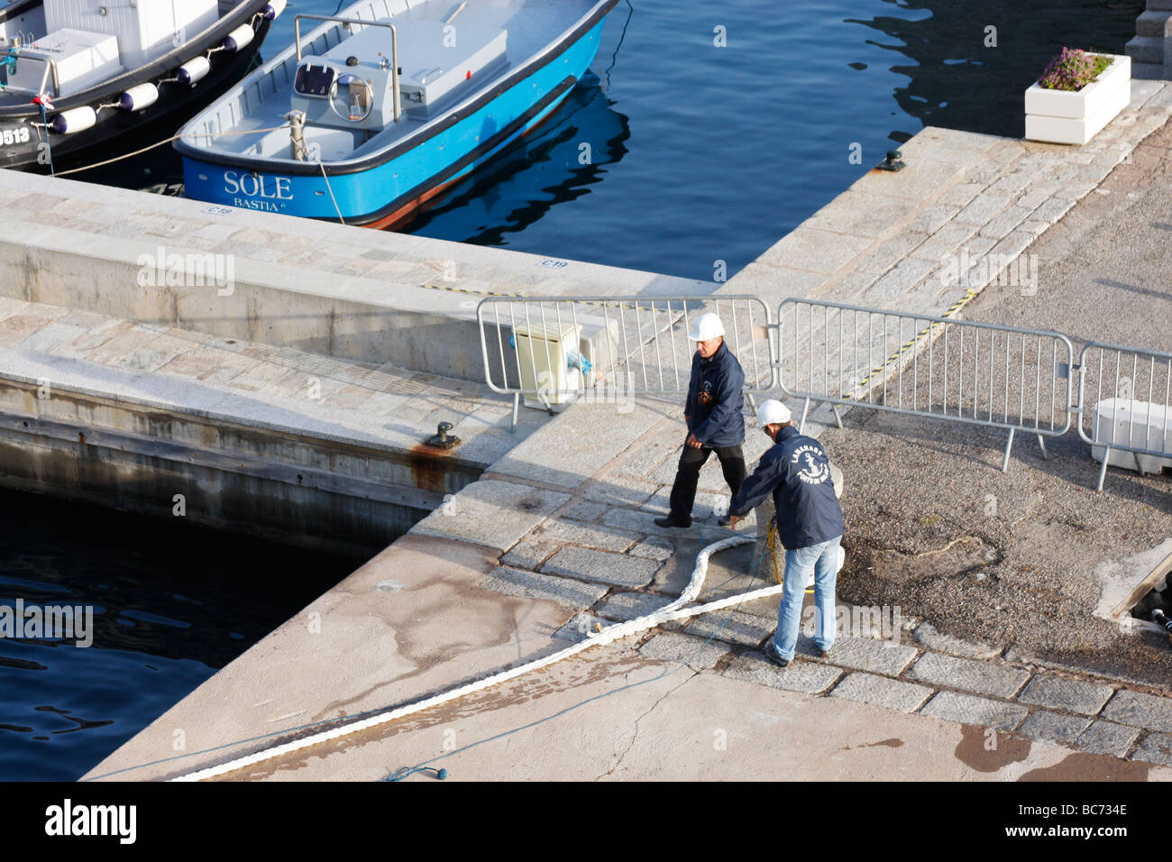 Dock workers making fast the mooring lines of a cruise ship at Calvi ...
