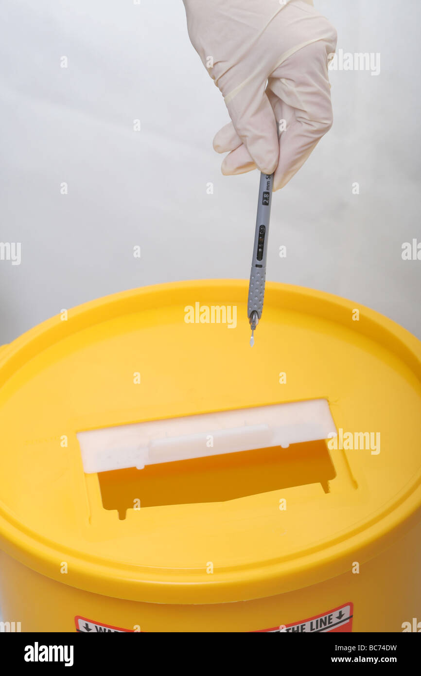 Nurse disposing of surgical instrument in hospital "sharps" disposal ...