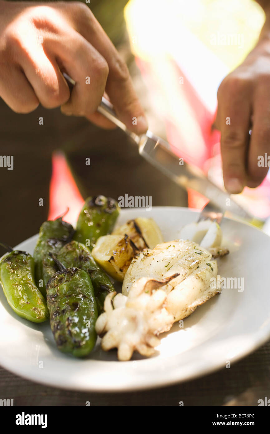 Man eating grilled cuttlefish with chillies Stock Photo - Alamy