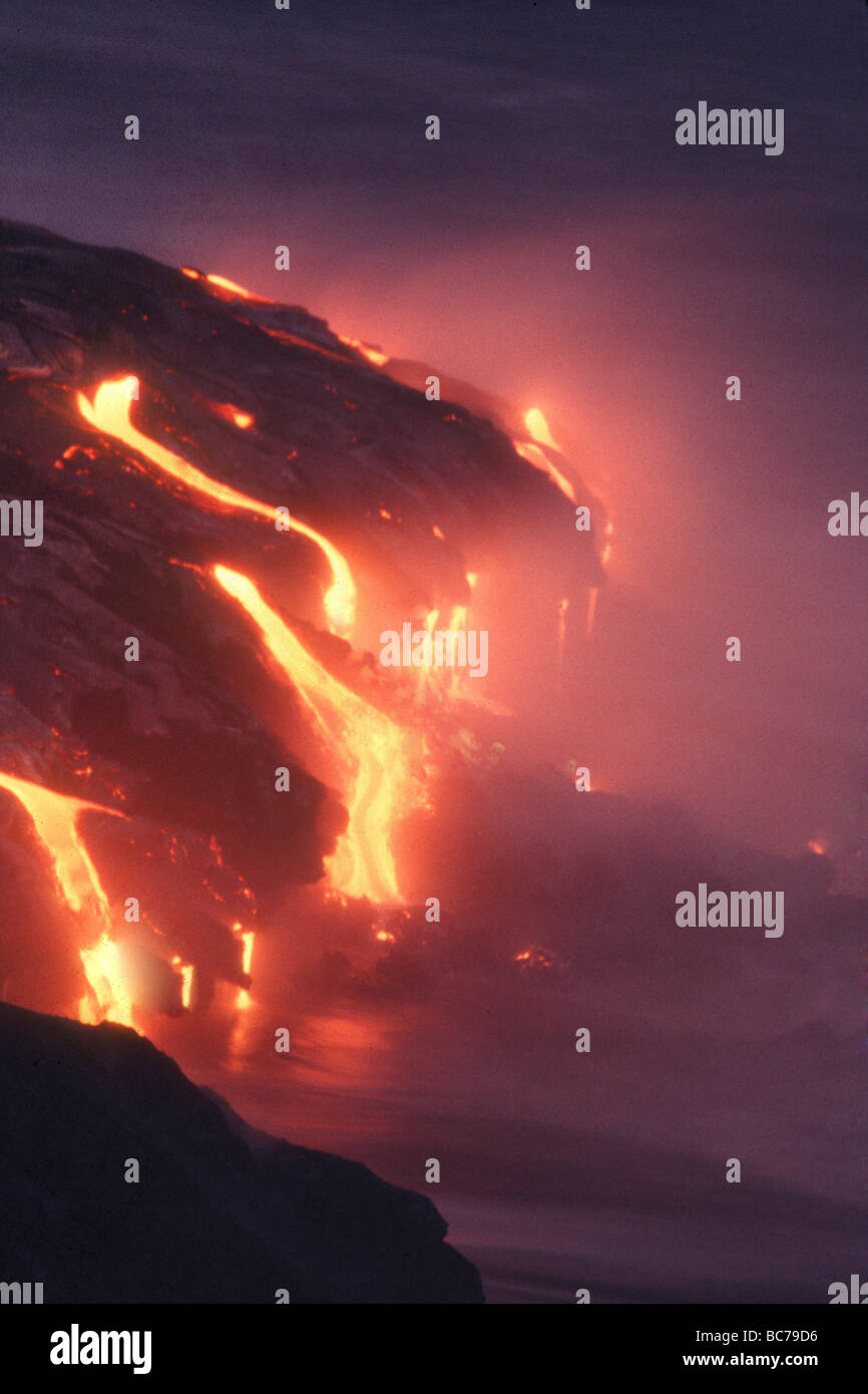 Lava from an active volcano flowing into the sea over a cliff edge at ...