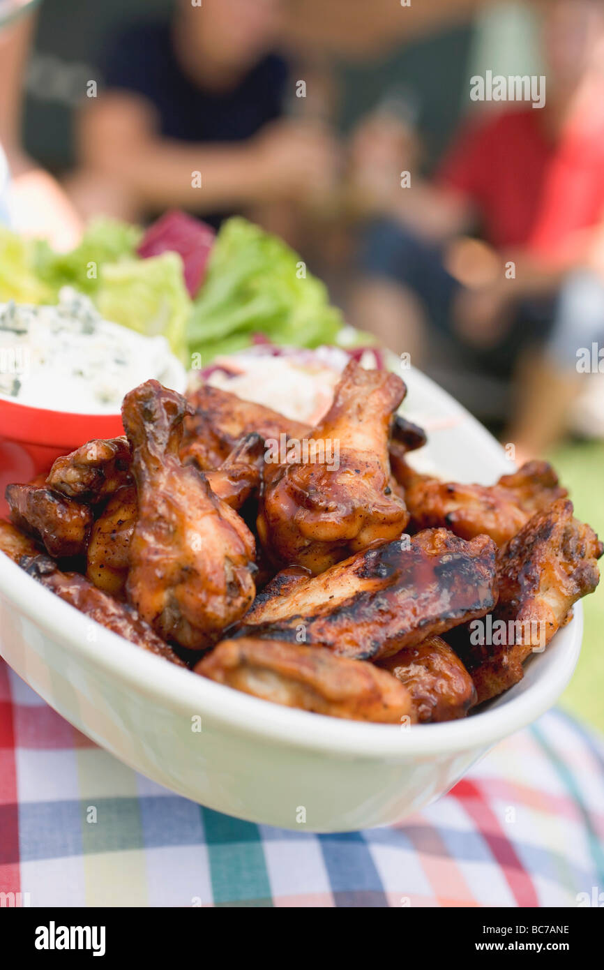 Person holding grilled chicken wings, people in background Stock Photo ...