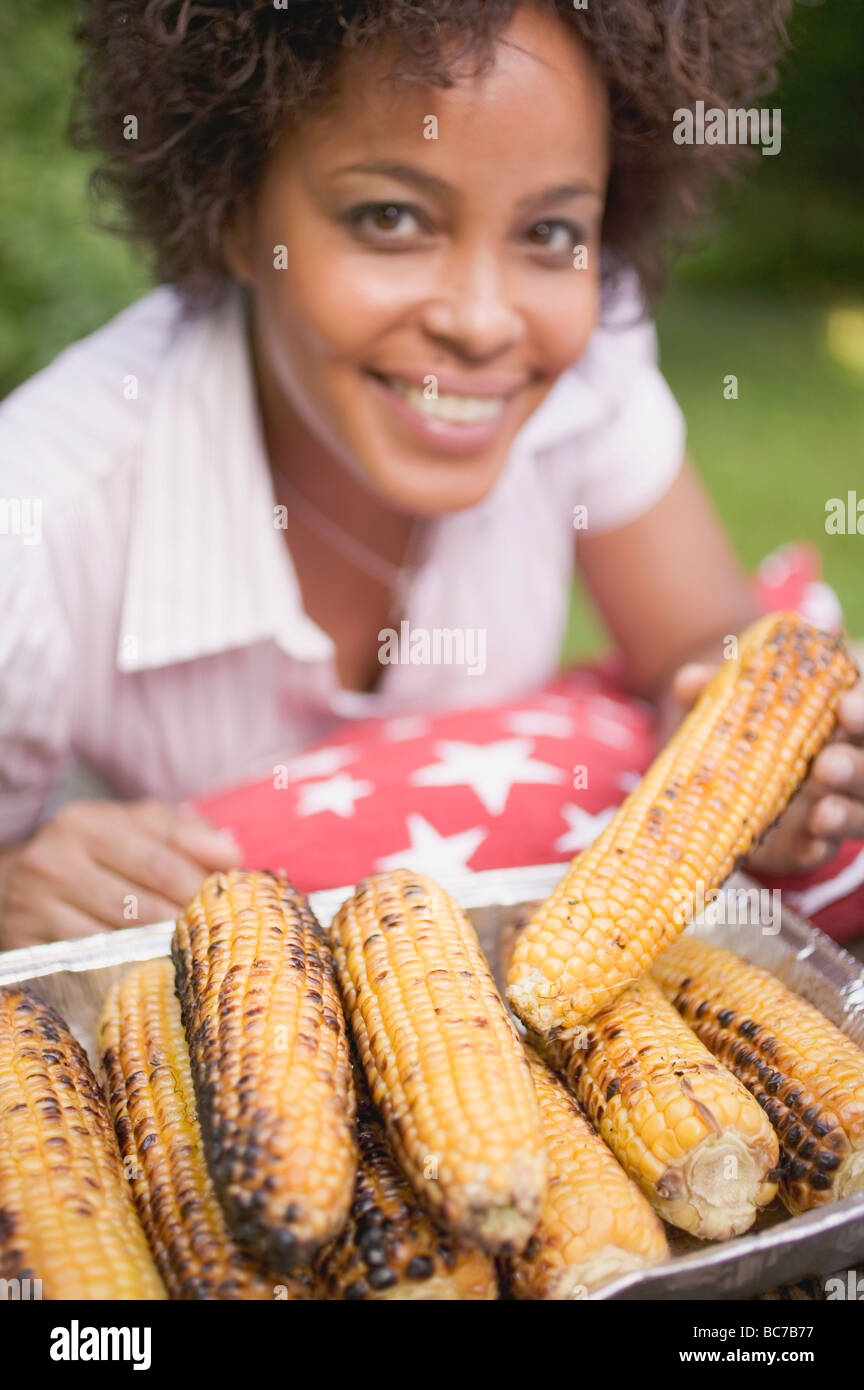 Woman taking grilled corn on the cob out of aluminium dish Stock Photo ...