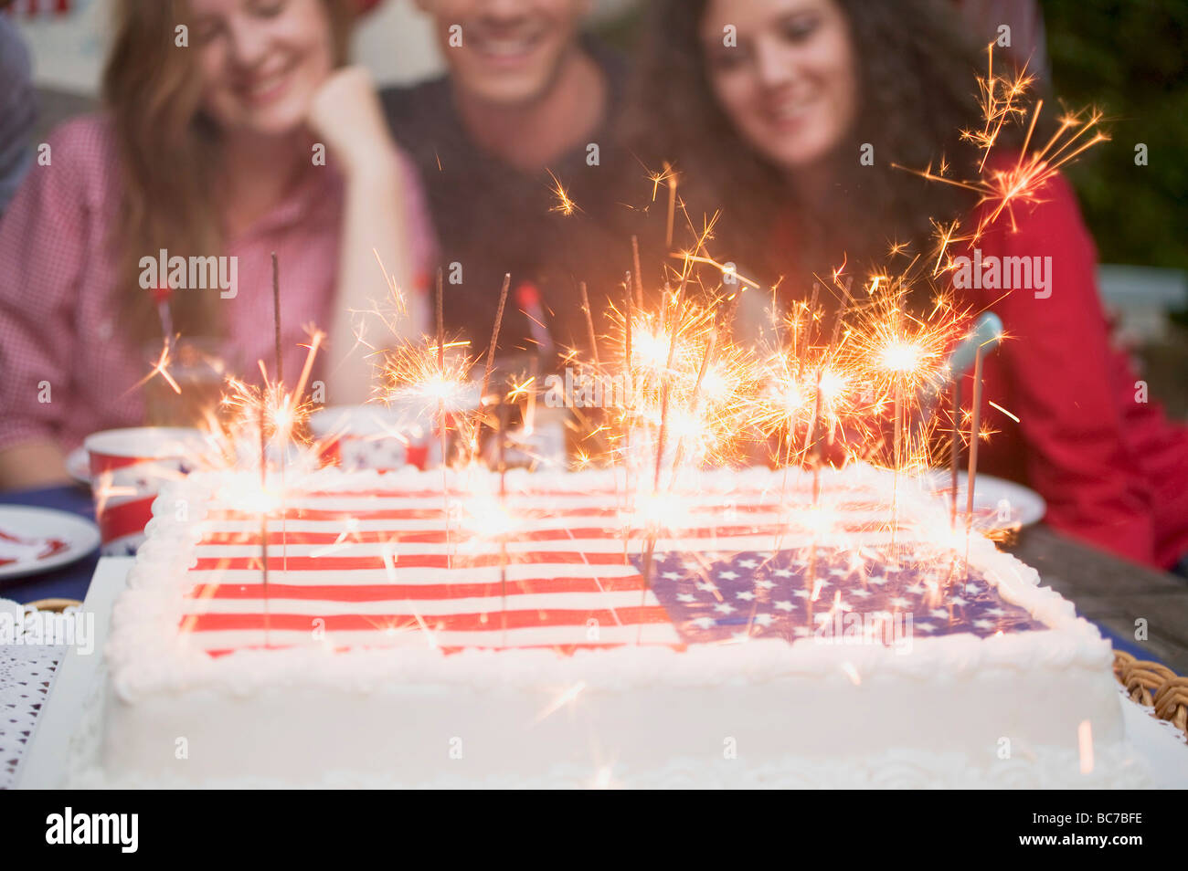 Young people behind cake with sparklers (4th of July, USA Stock Photo ...