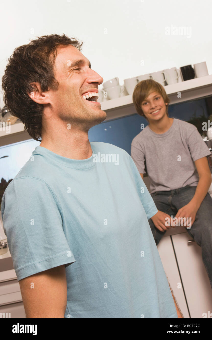 Father and son (13-14), Man laughing, boy watching in background Stock ...