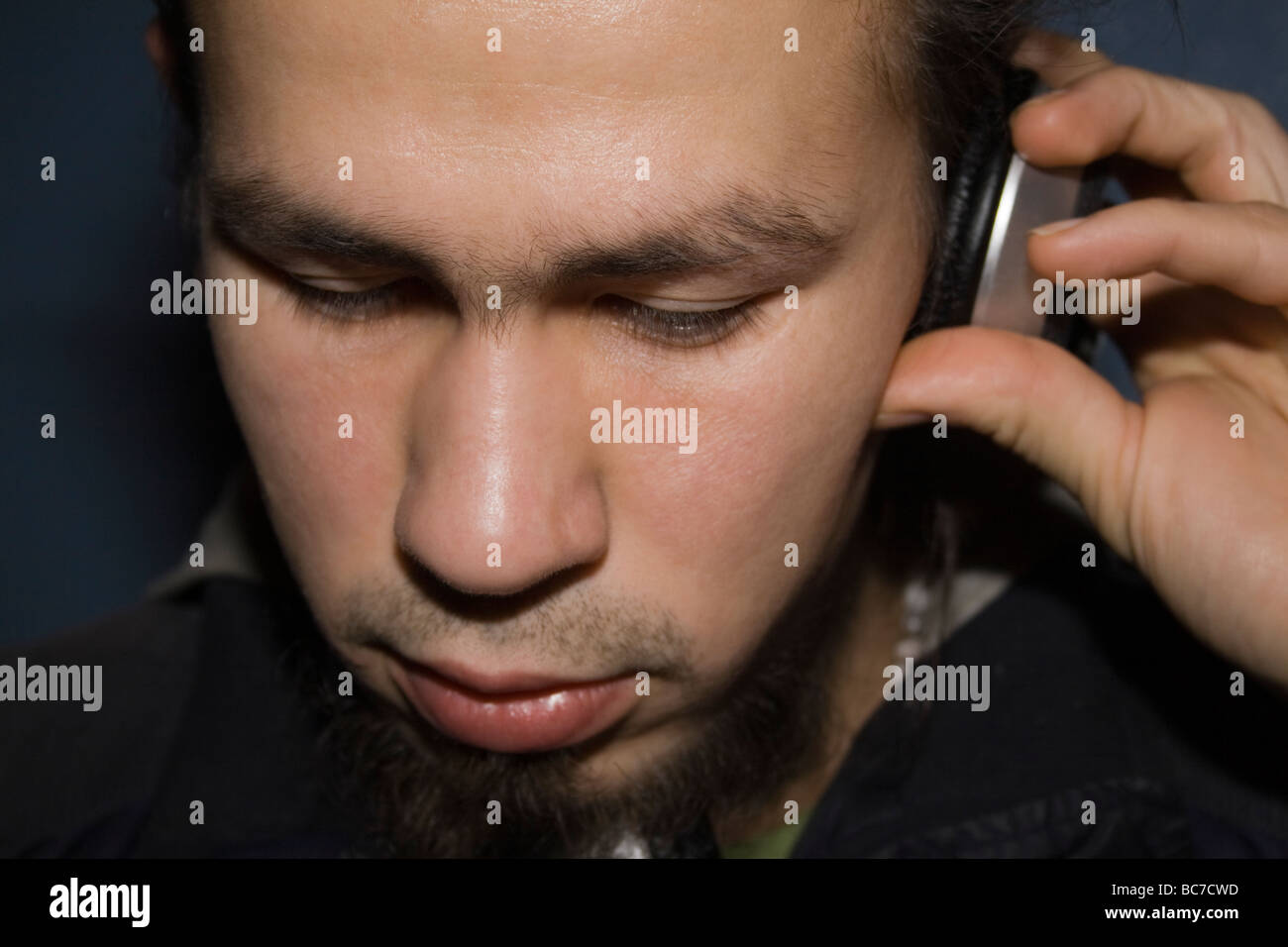 Young man DJ holding one hand on the headphones, he has a small beard ...