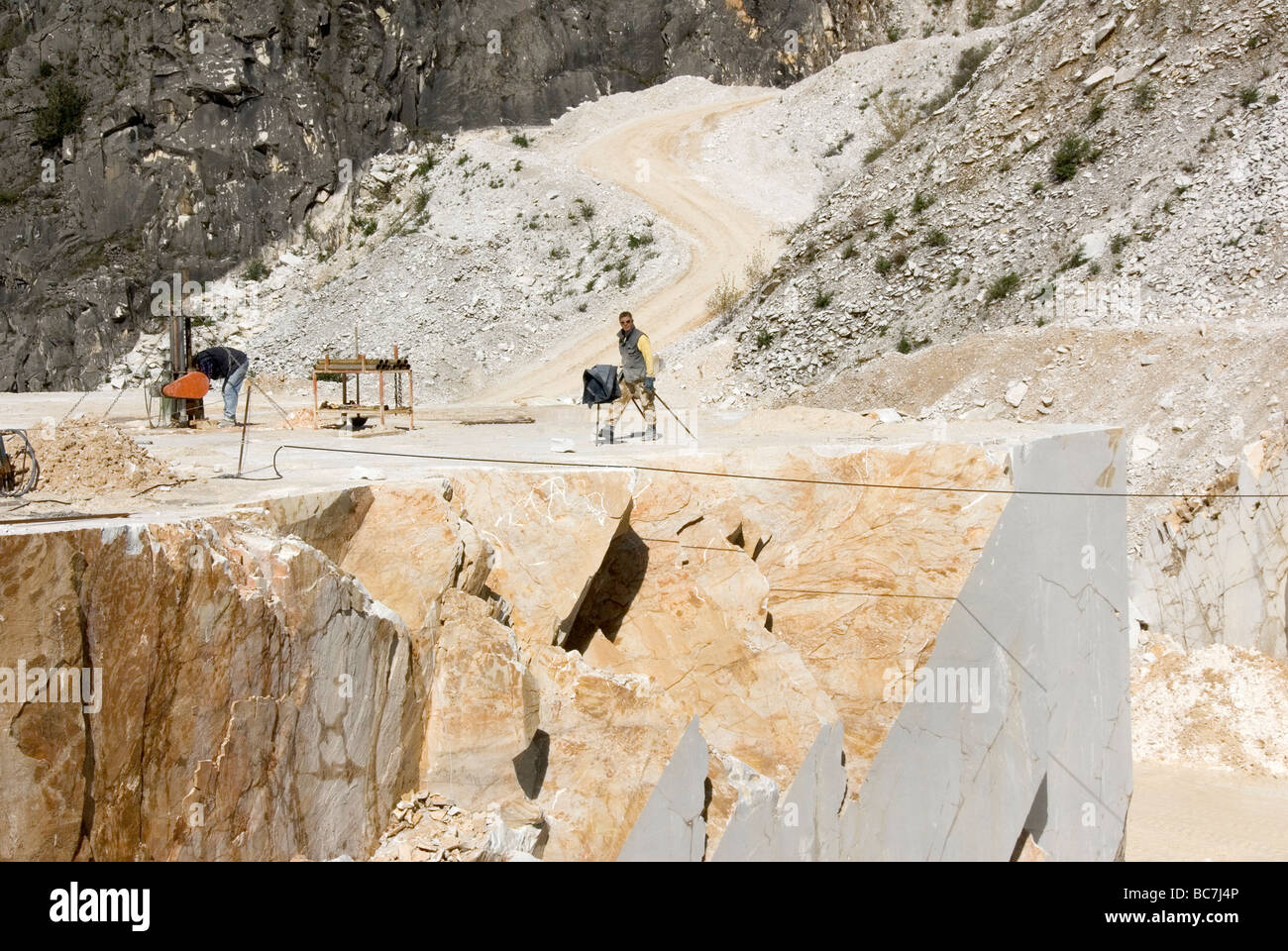 Two workers setting up drills to cut through the marble in the Carrara ...