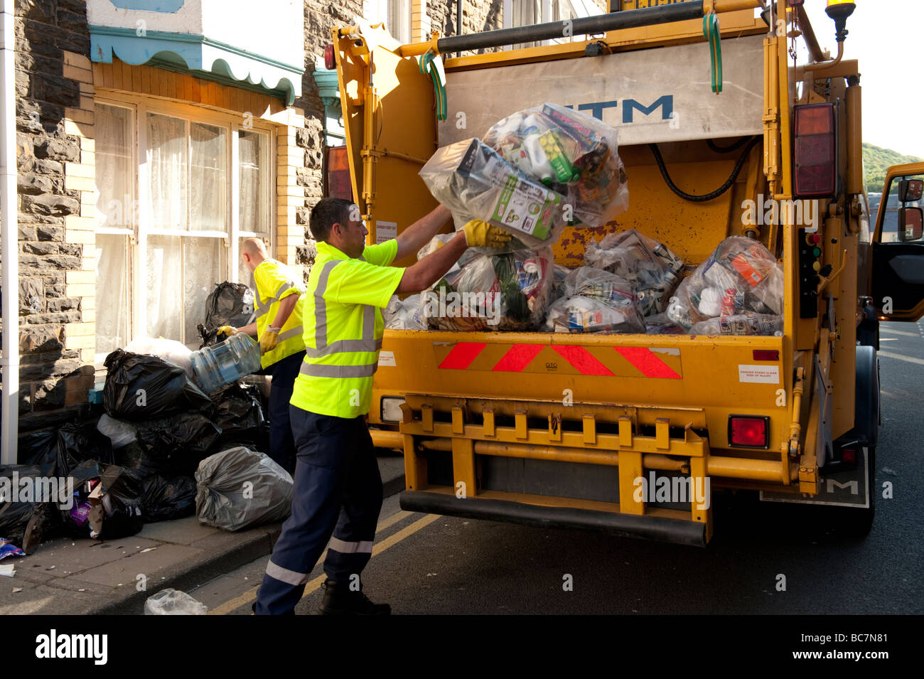 Local authority workers collecting recycling in a bag waste paper and ...