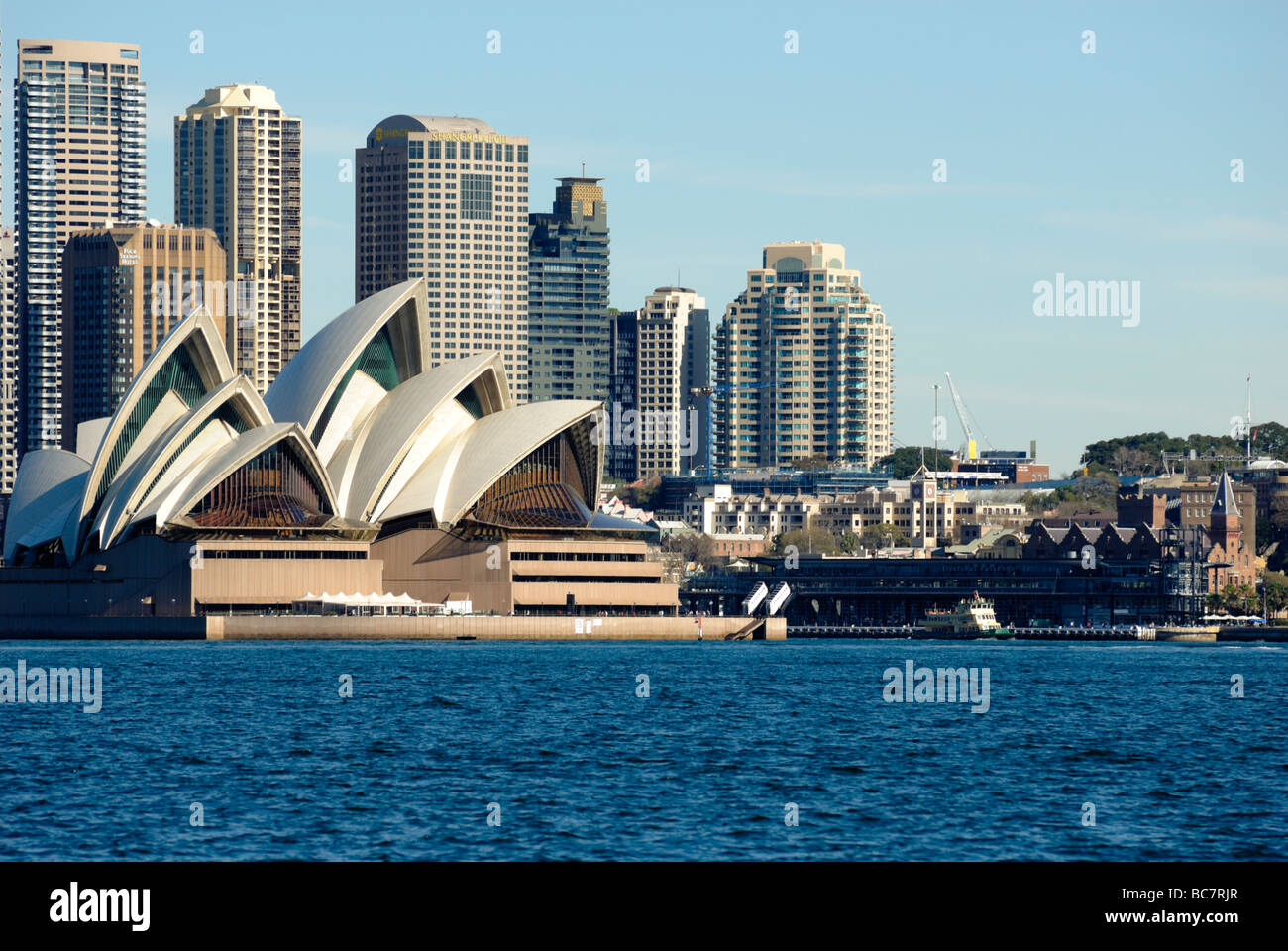 Sydney Opera House, with the blue water of Sydney Harbour in front and ...