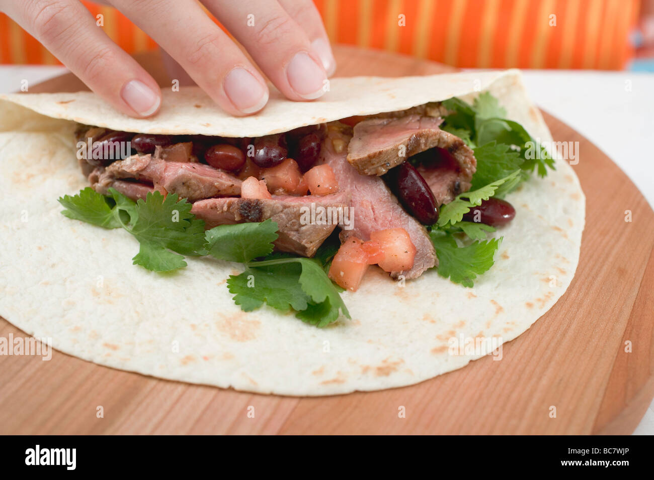 Hand folding tortilla over beef filling Stock Photo - Alamy