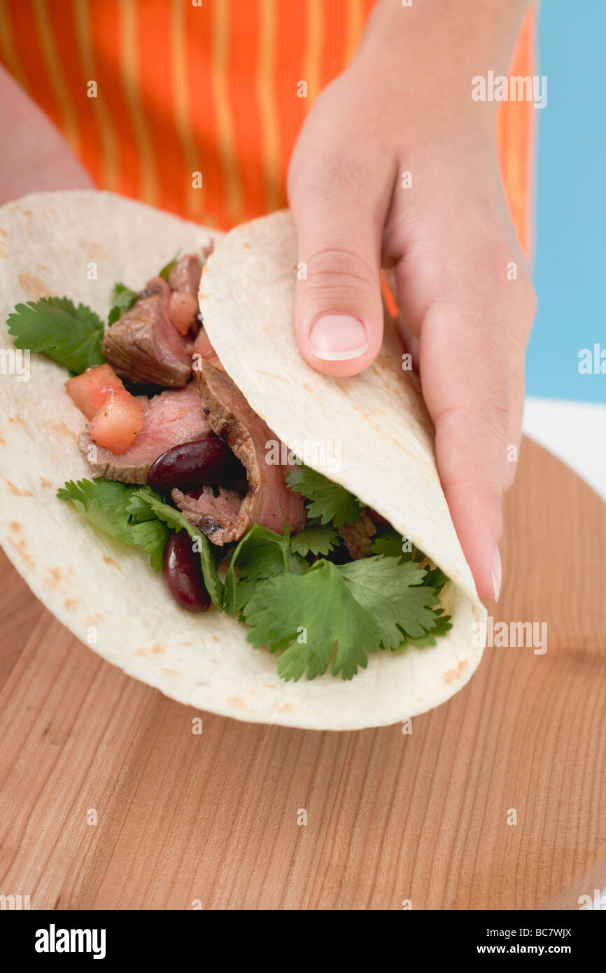 Hand folding tortilla over beef filling Stock Photo - Alamy